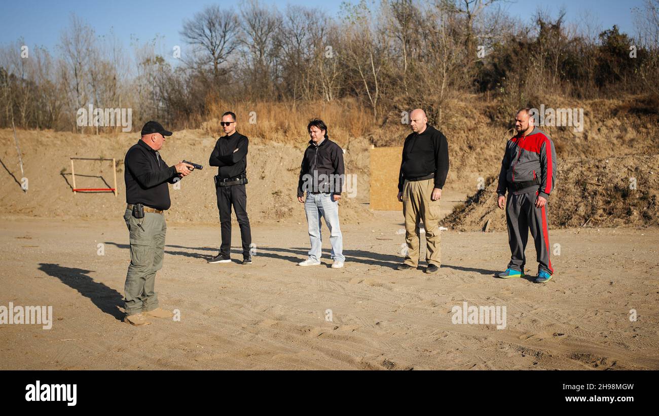 Shooting range instructor demonstrate gun shoot techniques to group of ...