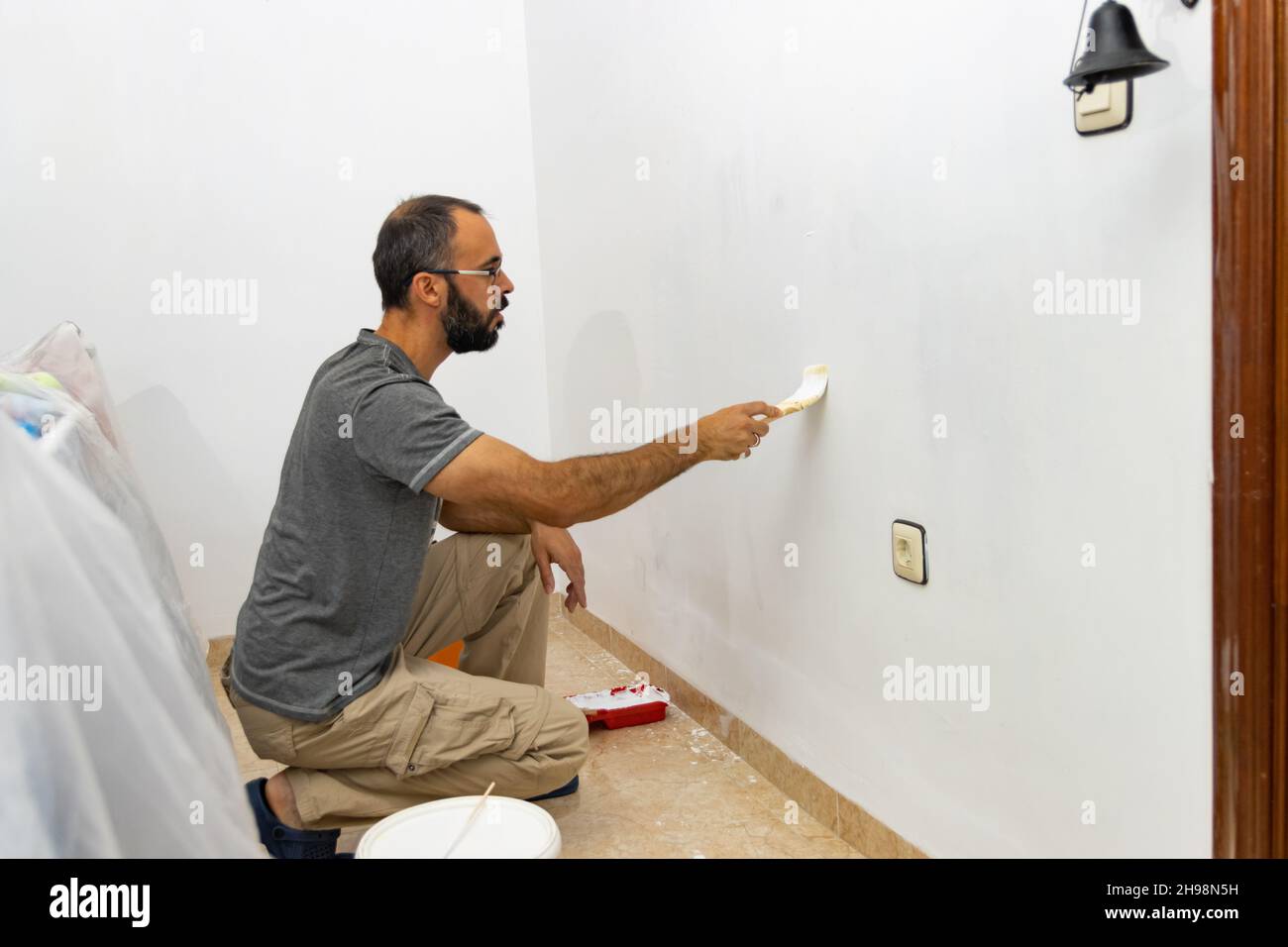 Man painting house walls white Stock Photo - Alamy