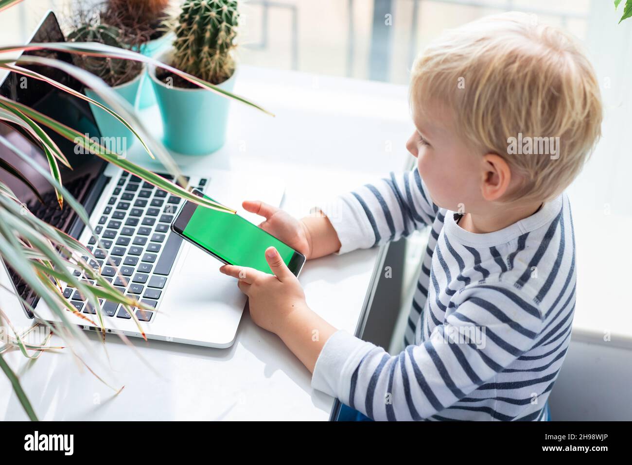 Cute baby boy watching, playing on the phone, focus on chromakey green ...