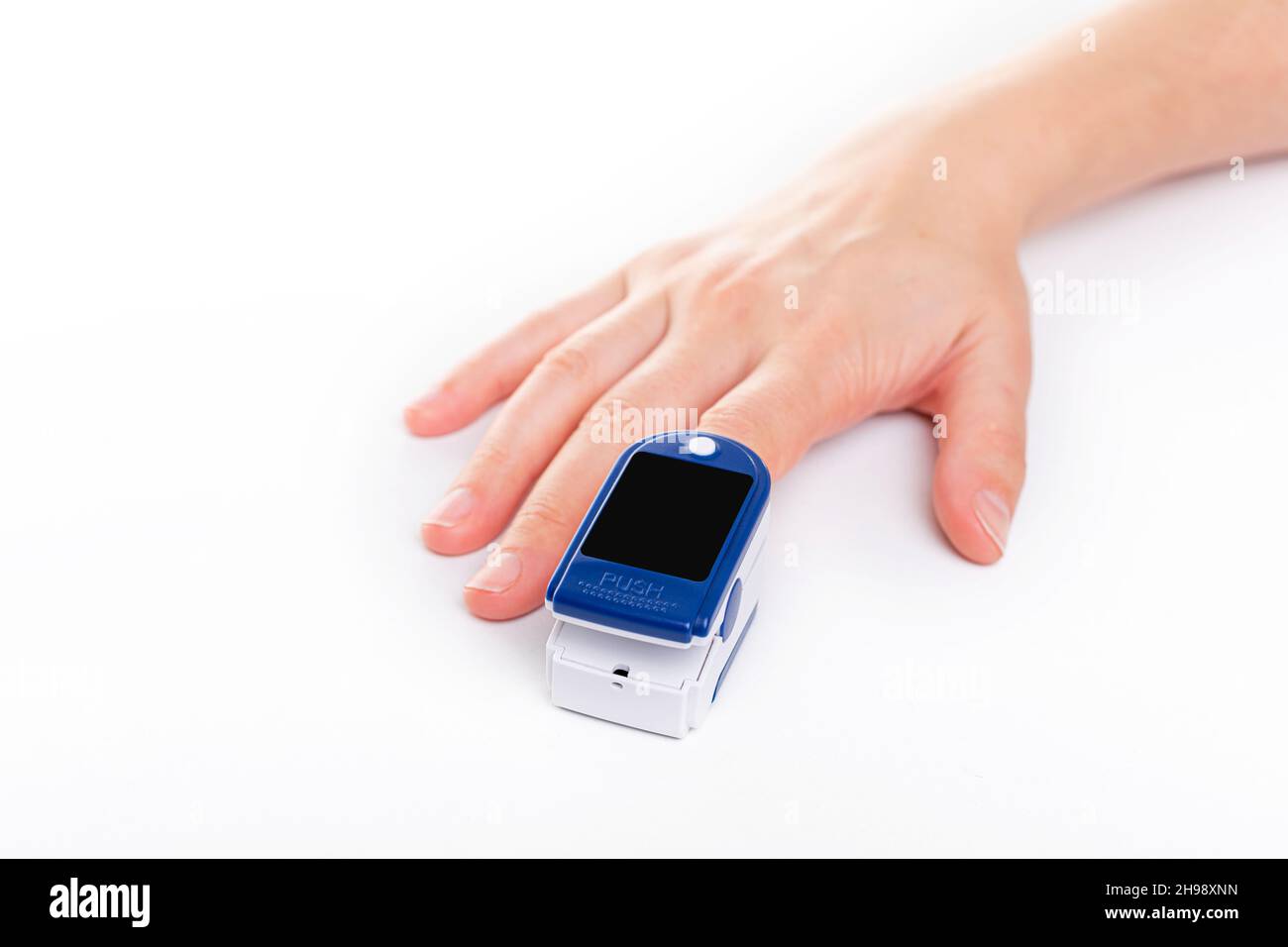 Pulse oximeter on a finger on white background Stock Photo - Alamy