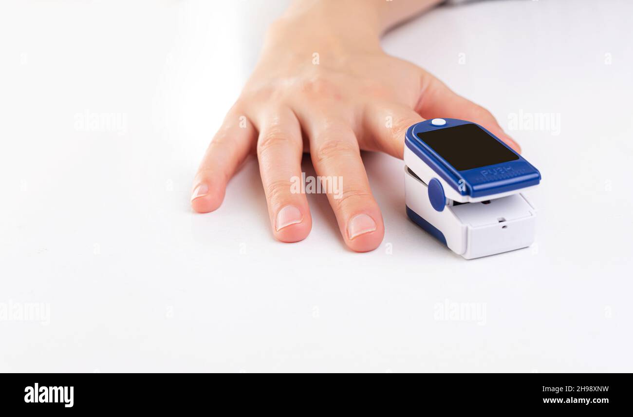 Pulse oximeter on a finger on white background Stock Photo - Alamy