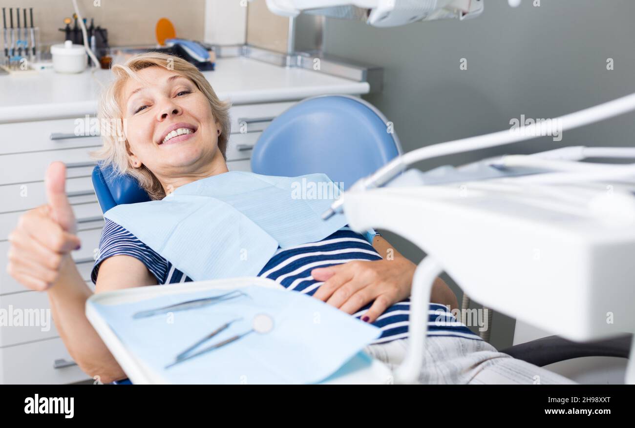 Satisfied woman visiting dentist giving thumbs up Stock Photo - Alamy