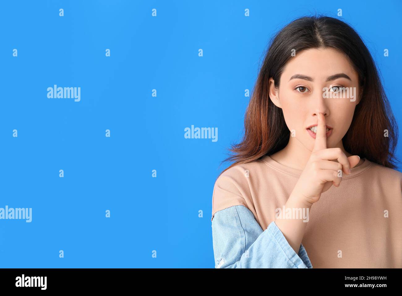 Young Asian woman showing silence gesture on color background Stock ...
