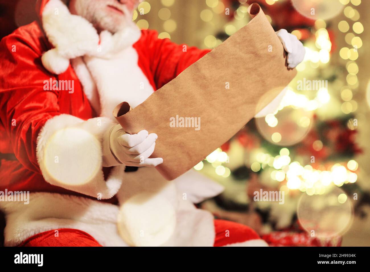 Santa Claus's hands are holding a list of children's wishes against the ...