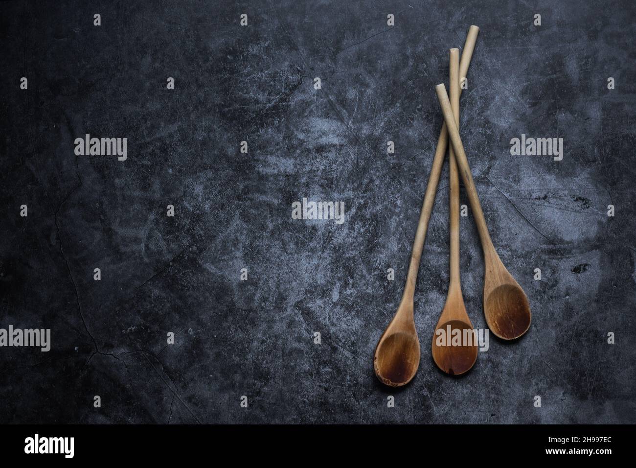 A flat lay view of wooden kitchen spoons on gray background with copy ...