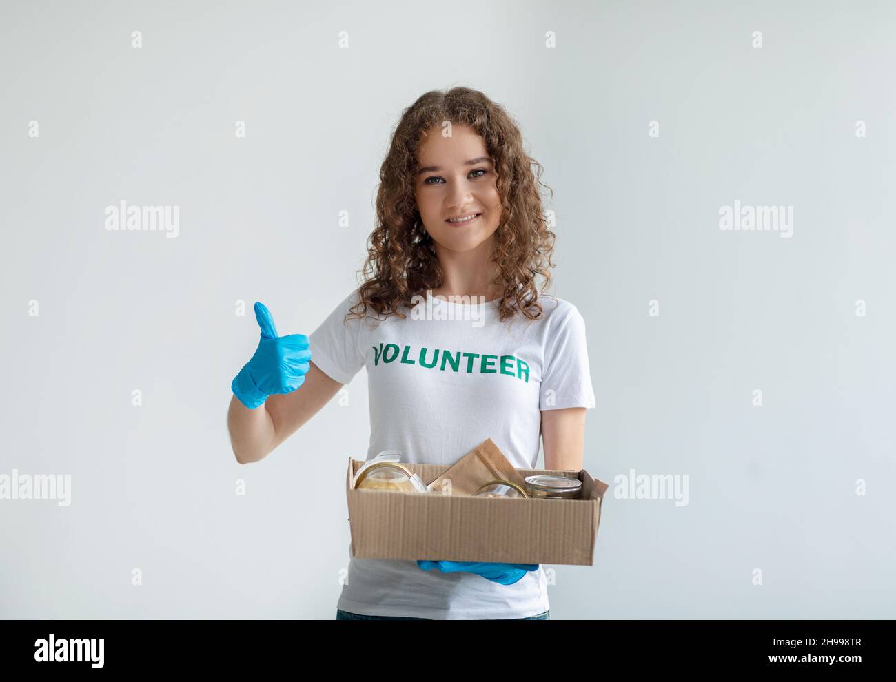 Excited activist volunteer holding box with donations and showing thumb ...