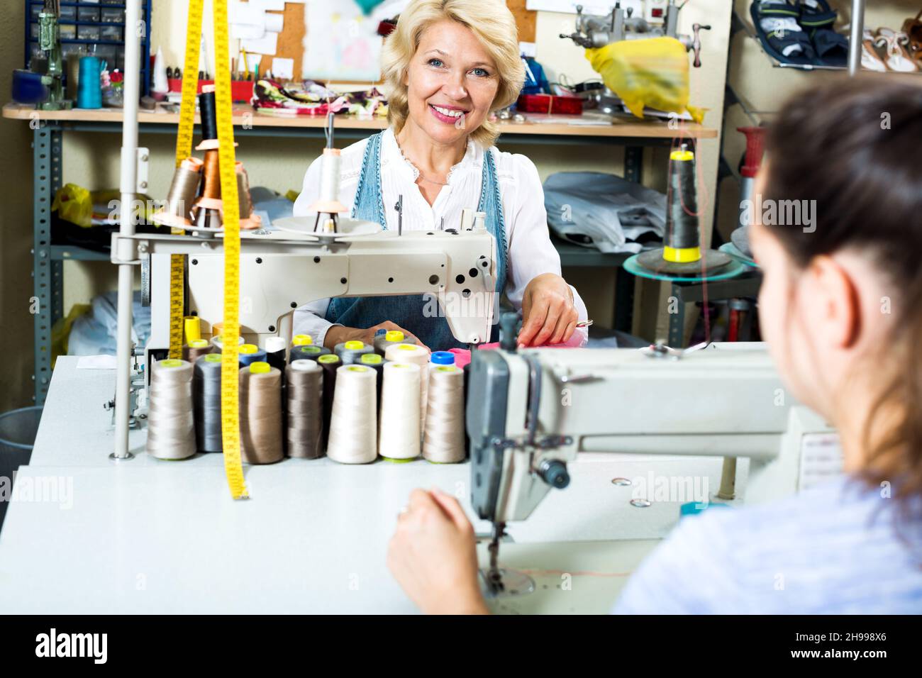Two women sewing with professional equipment Stock Photo - Alamy