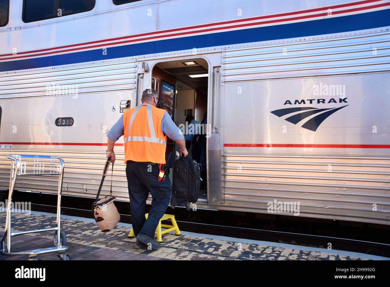 An Amtrak employee in Lamy, New Mexico, loads luggage into the ...