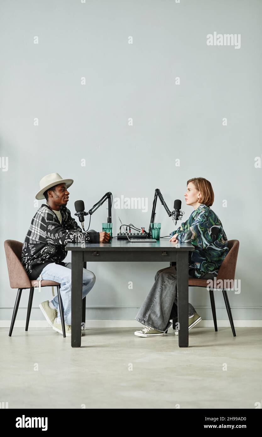Vertical full length portrait of two people speaking to microphones ...