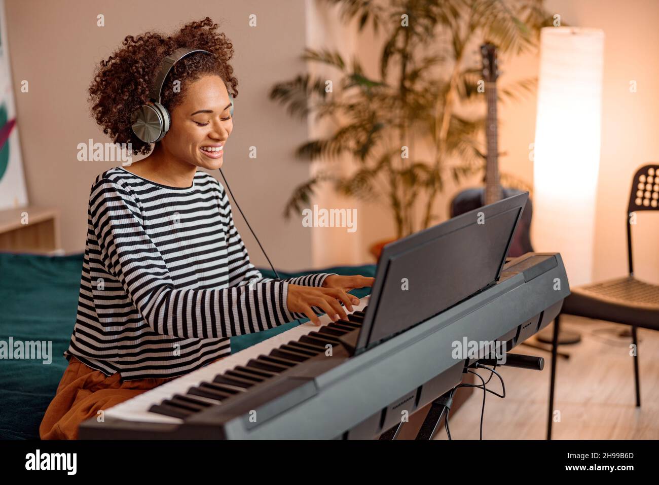 Cheerful female musician playing synthesizer at home Stock Photo - Alamy