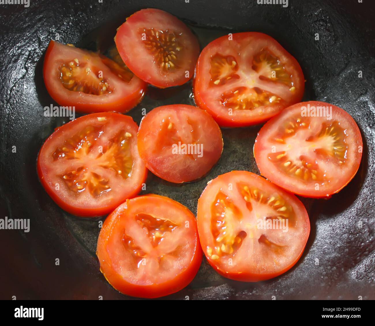 Fresh red tomatoes on the cast-iron pan during frying process Stock ...
