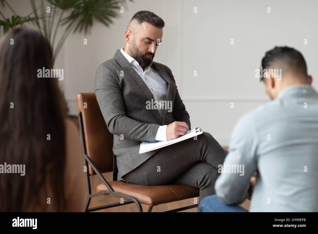 Couple sitting at therapy session with therapist, man taking notes ...