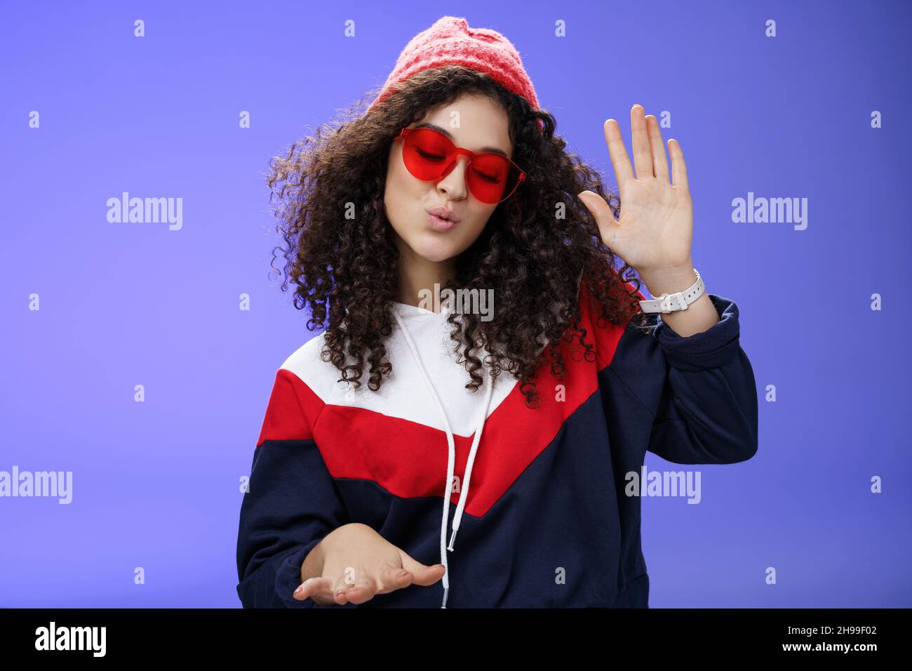 Studio shot of cool and stylish dj girl in red beanie and sunglasses ...