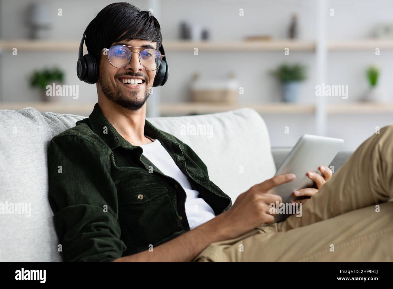 Joyful middle eastern young man chilling at home with tablet Stock ...