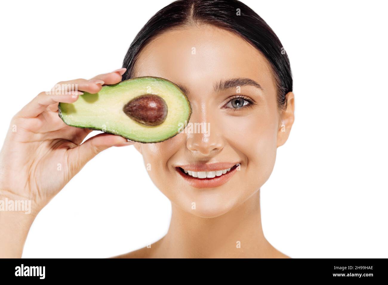 Pretty young woman holding half an avocado in front of her face. Photo ...