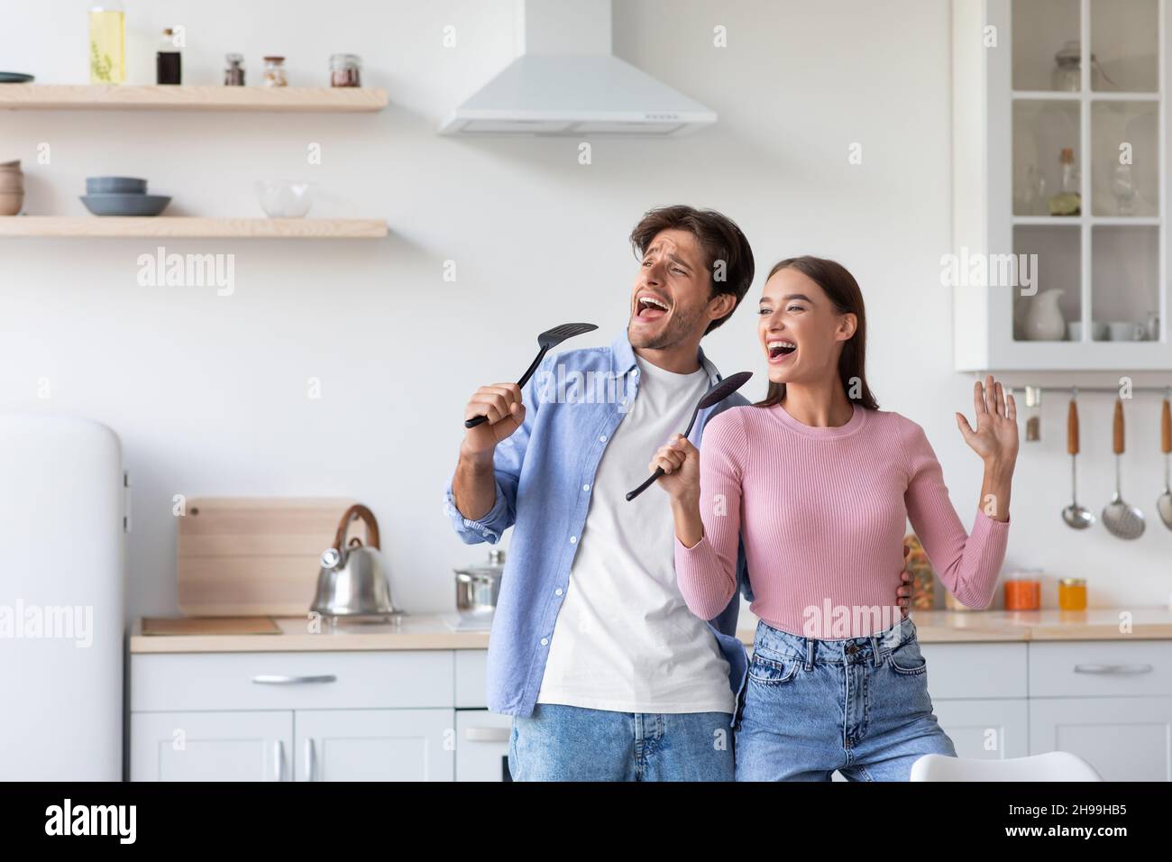 Smiling young caucasian male and female have fun, sing song at ...