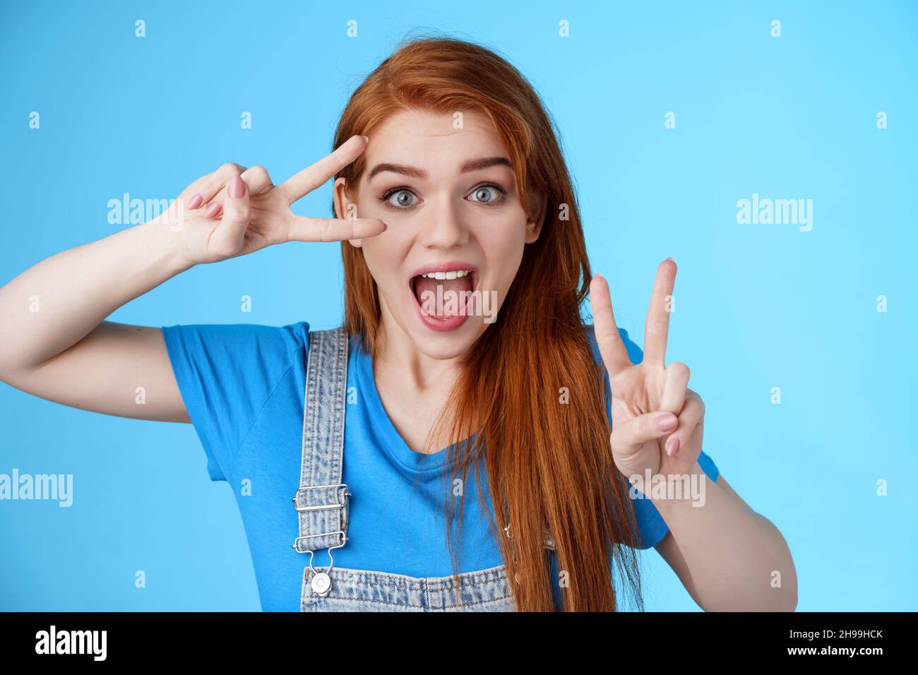 Cute excited redhead enthusiastic girl smiling, look joyful show peace ...