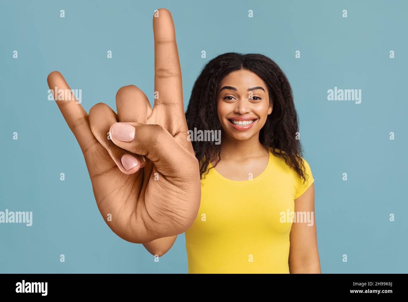 Happy African American woman gesturing big rock sign, looking and ...