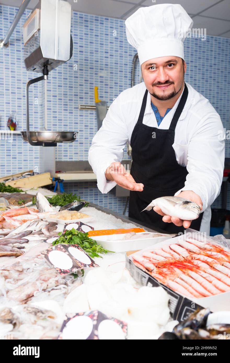 Happy seller shows hands fish on counter Stock Photo - Alamy