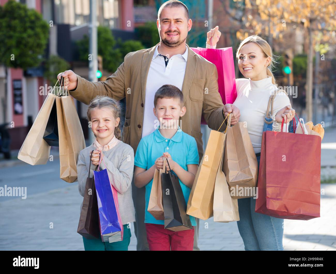 Happy family with two kids holding shopping bags Stock Photo - Alamy