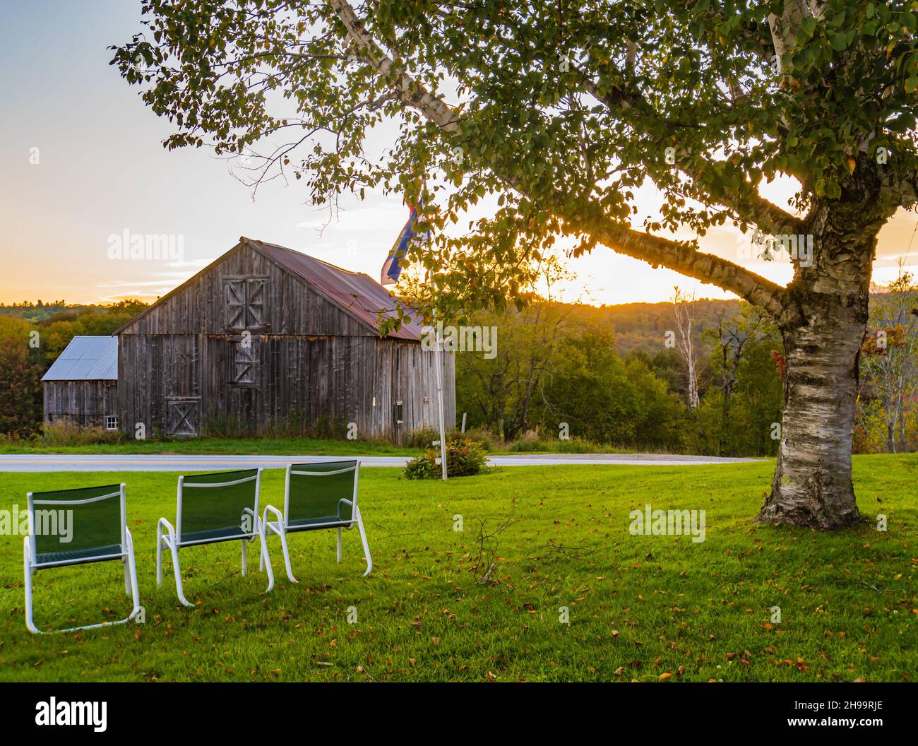 rustic gray barn back lit by the setting sun on a country road Stock ...