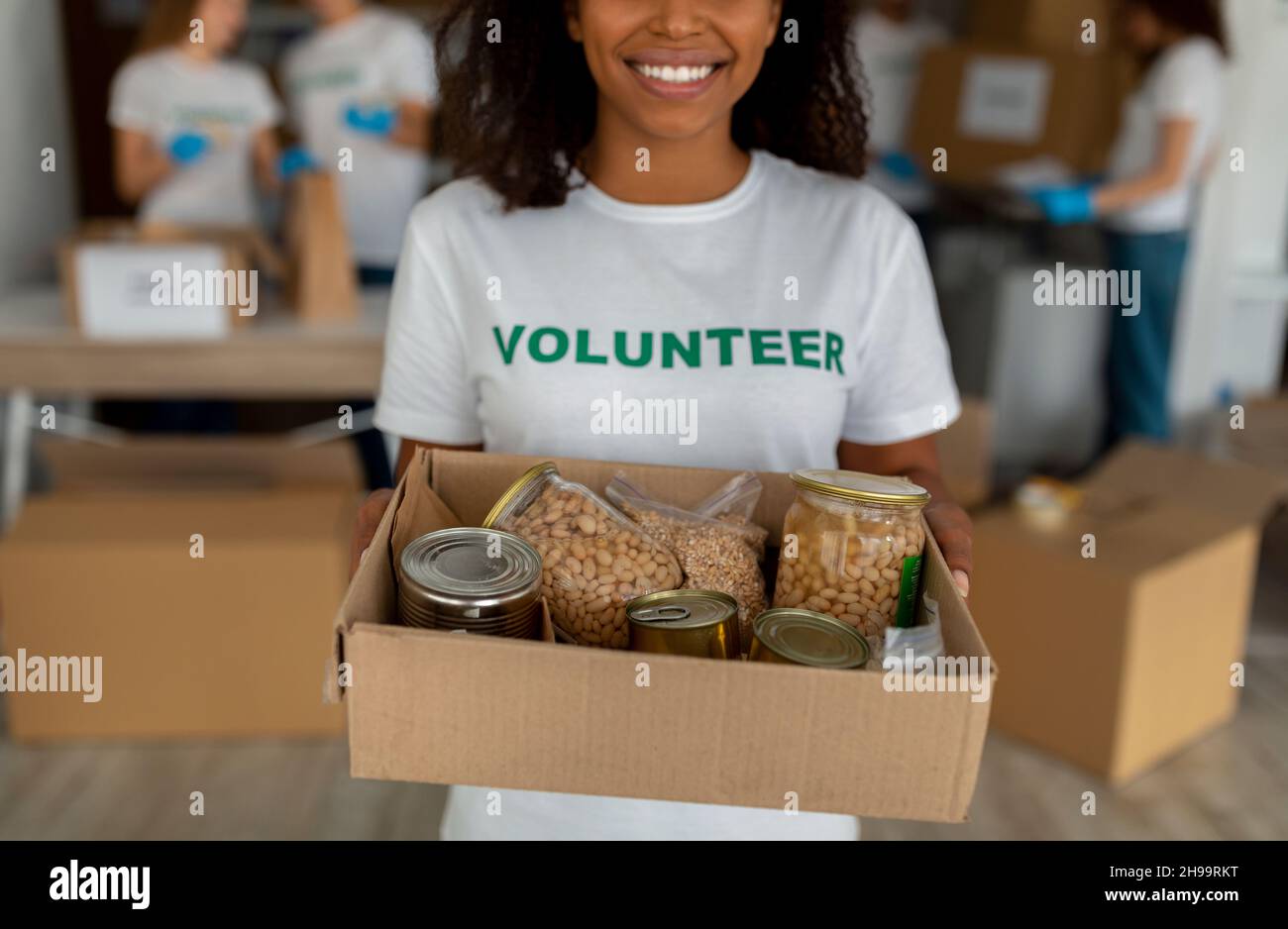 Humanitarian aid. Black female volunteer holding food donation box and ...