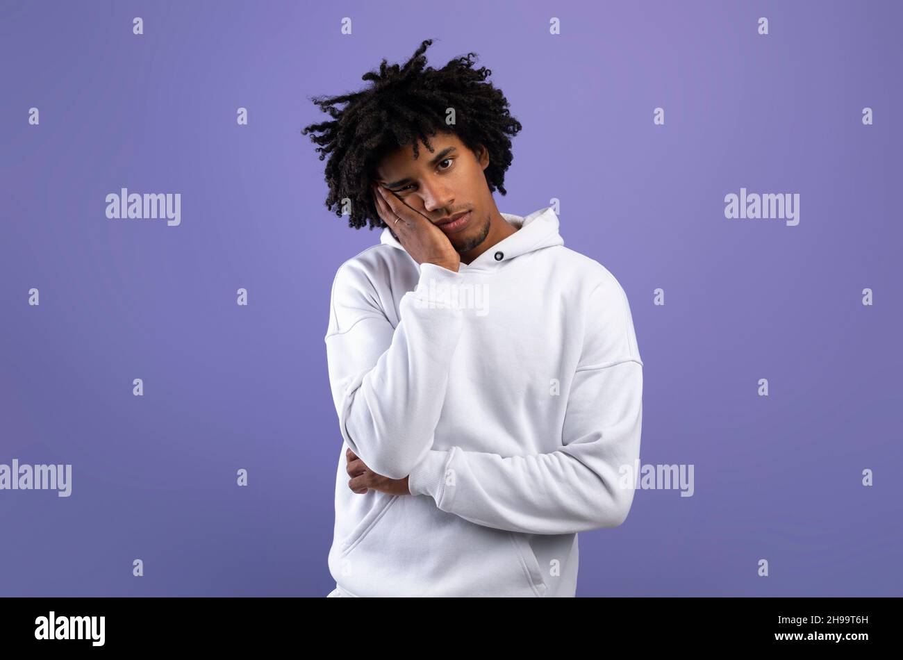 Portrait of black teen guy feeling bored, leaning on his hand, having ...