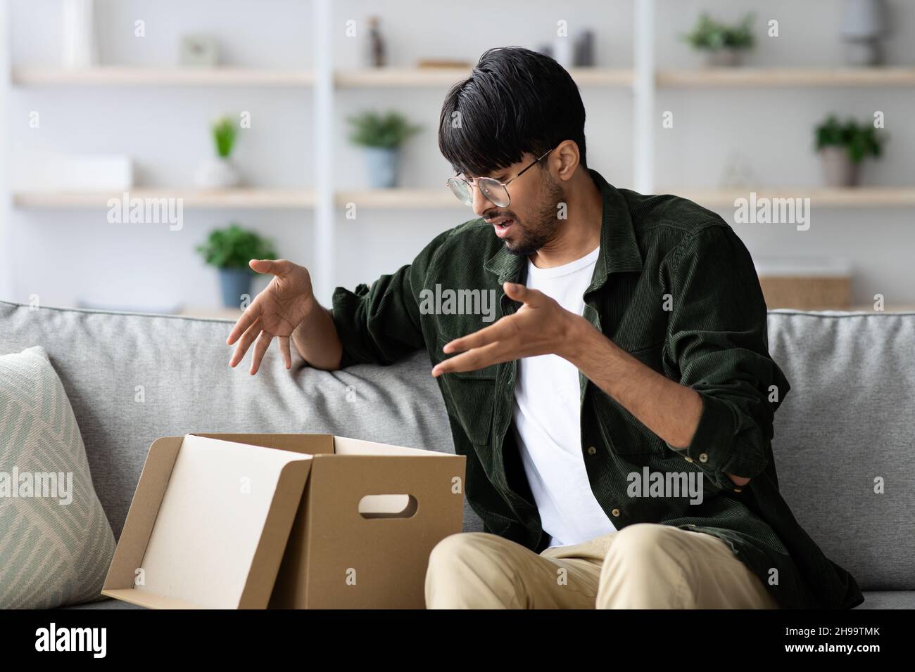 Angry young indian man opening box a home Stock Photo - Alamy