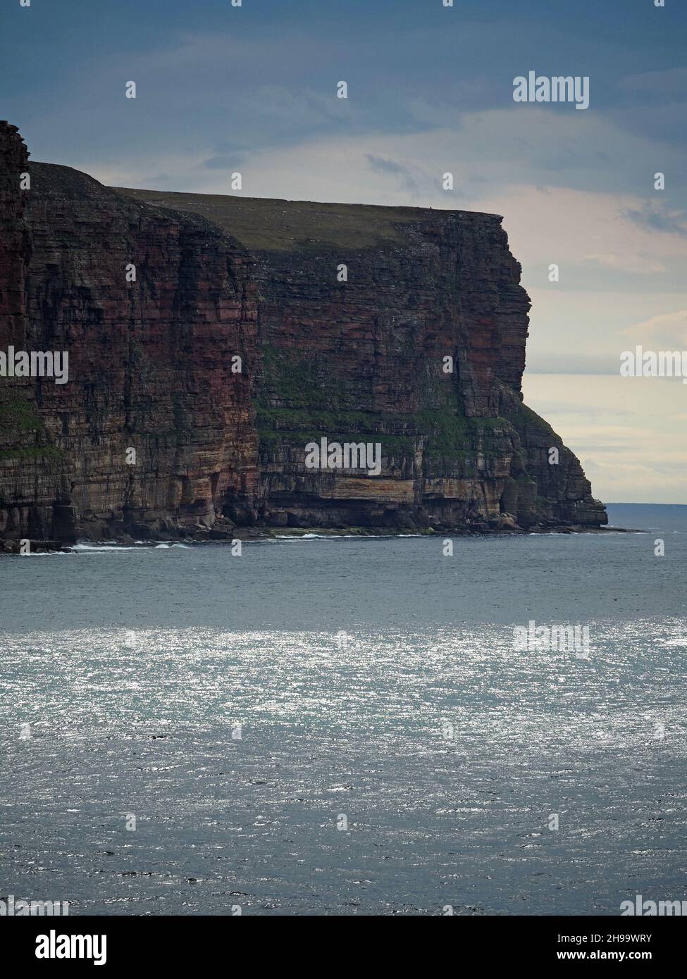 Towering rocky sea-cliffs above Rackwick Bay with silver light on the ...