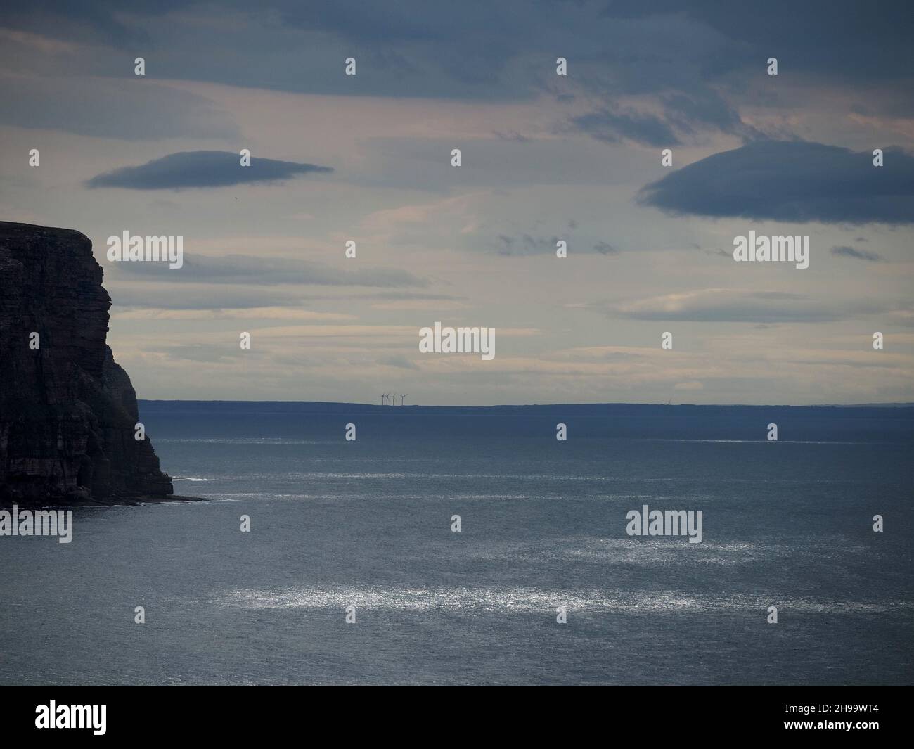 Towering rocky sea-cliffs above Rackwick Bay with silver light on the ...