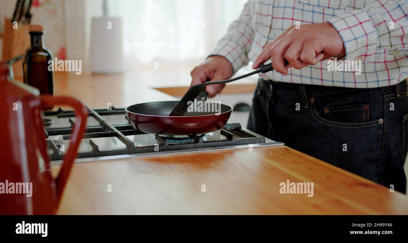 Hands of a man who is cooking with a frying pan Stock Photo - Alamy