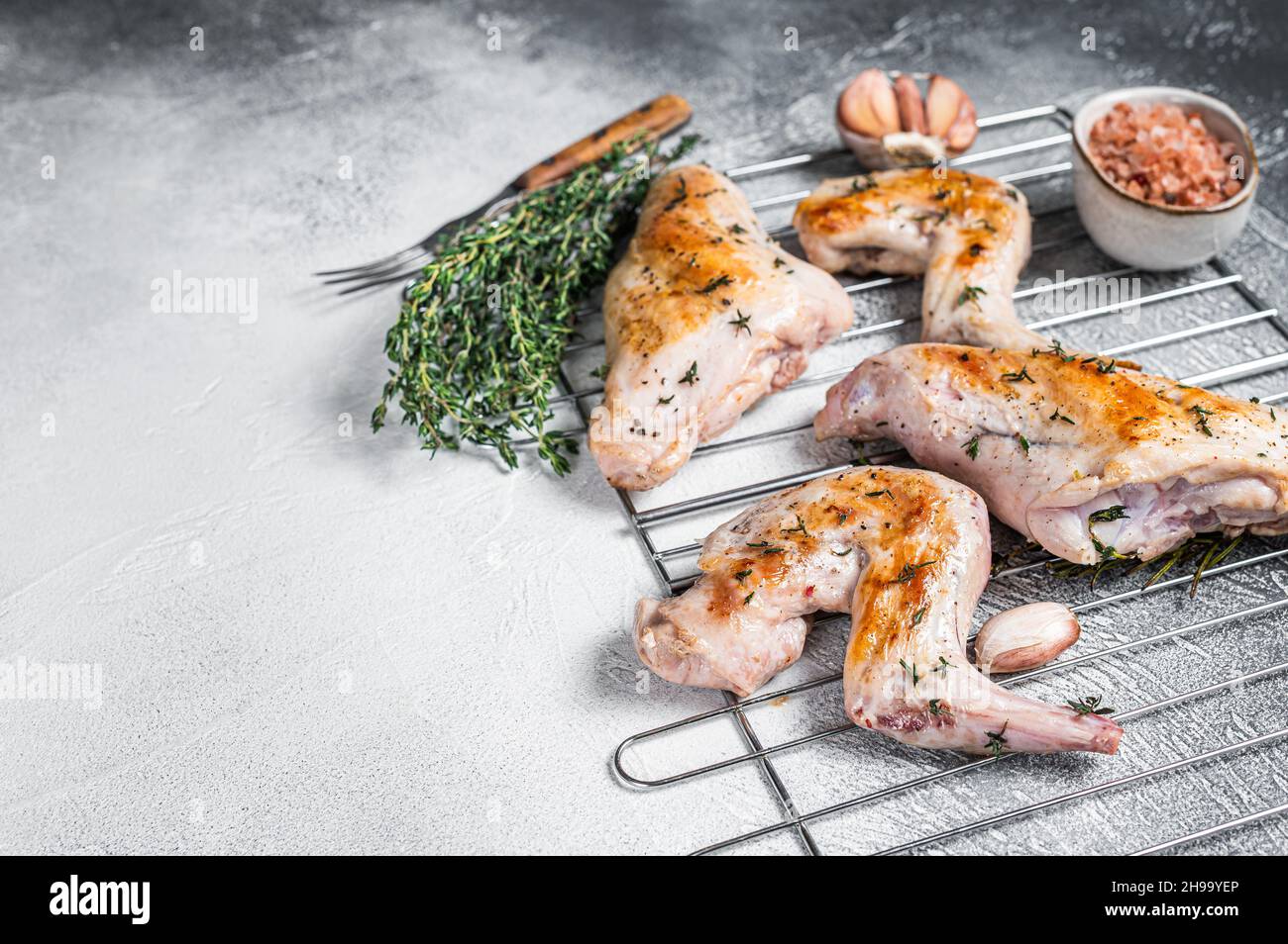 Baked rabbit legs on a grill with thyme. White background. Top view ...