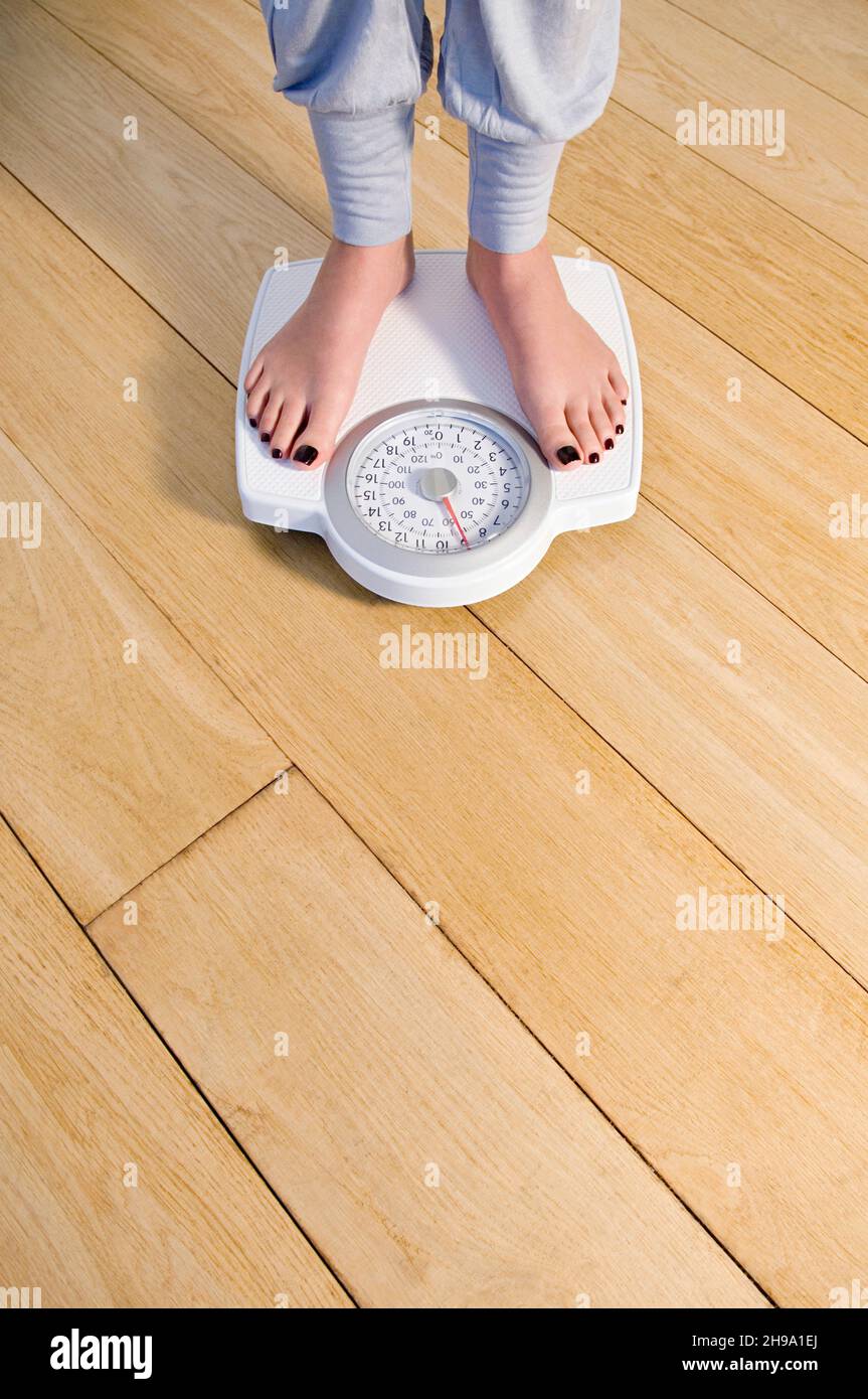 Woman standing on weighing scale, feet and lower legs Stock Photo - Alamy