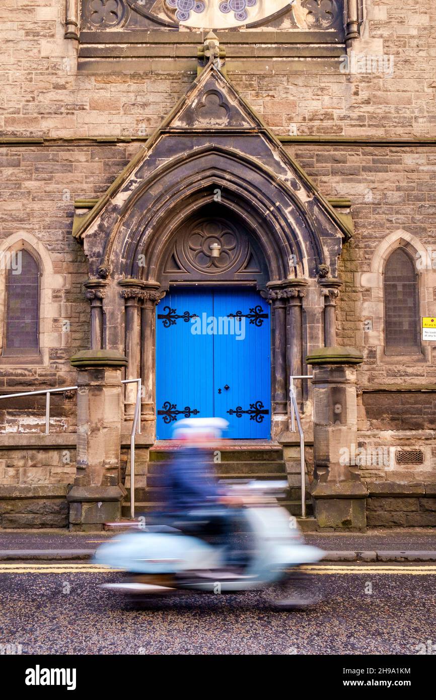Person on a scooter driving past a gothic arch with bright blue door ...