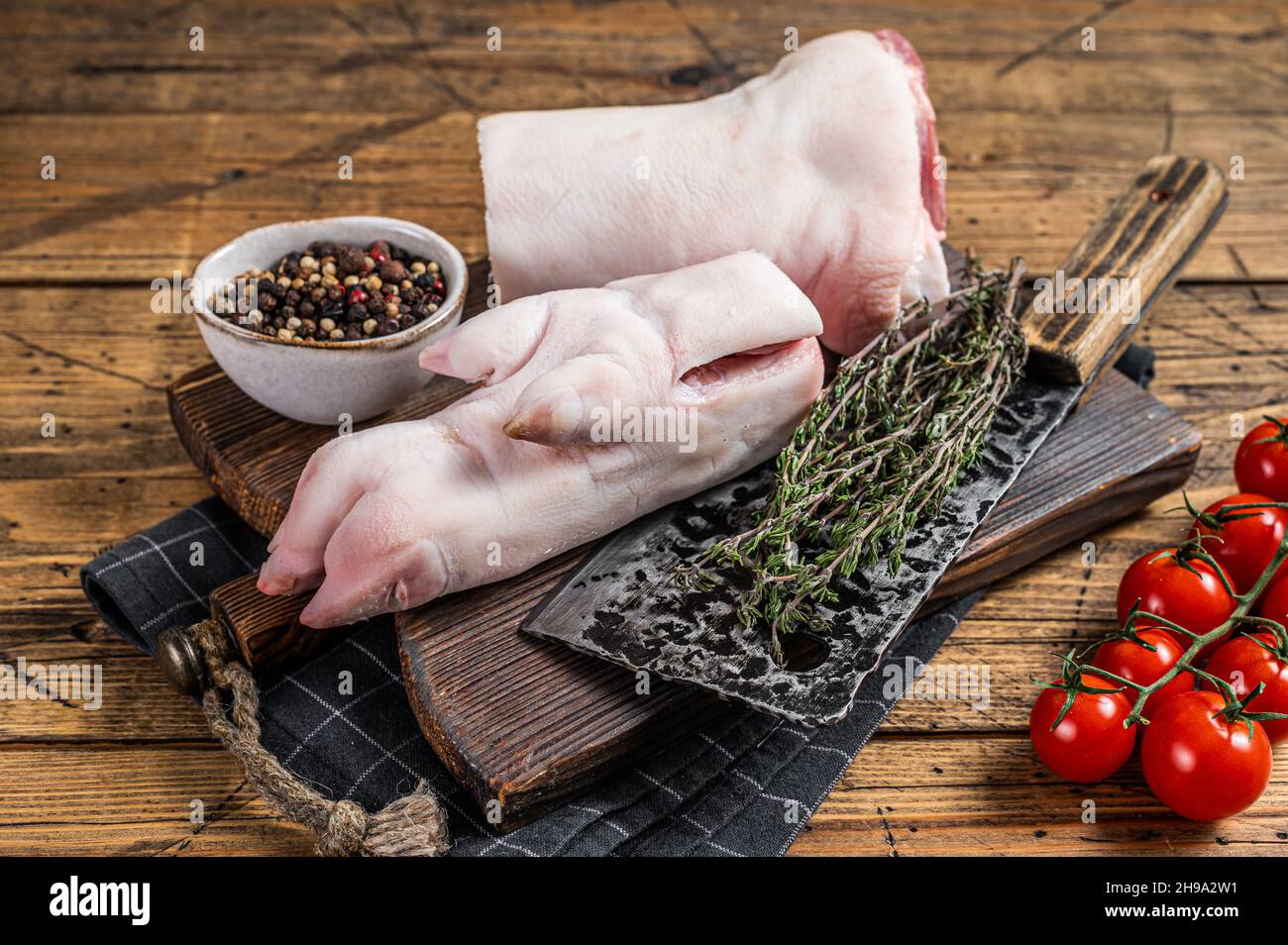 Fresh Raw pork knuckle or hoof, feet on a butcher board with cleaver ...