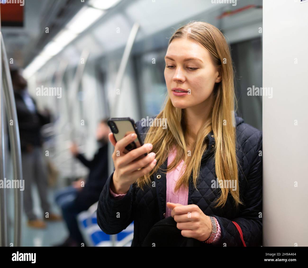 Girl using mobile phone in metro car Stock Photo - Alamy