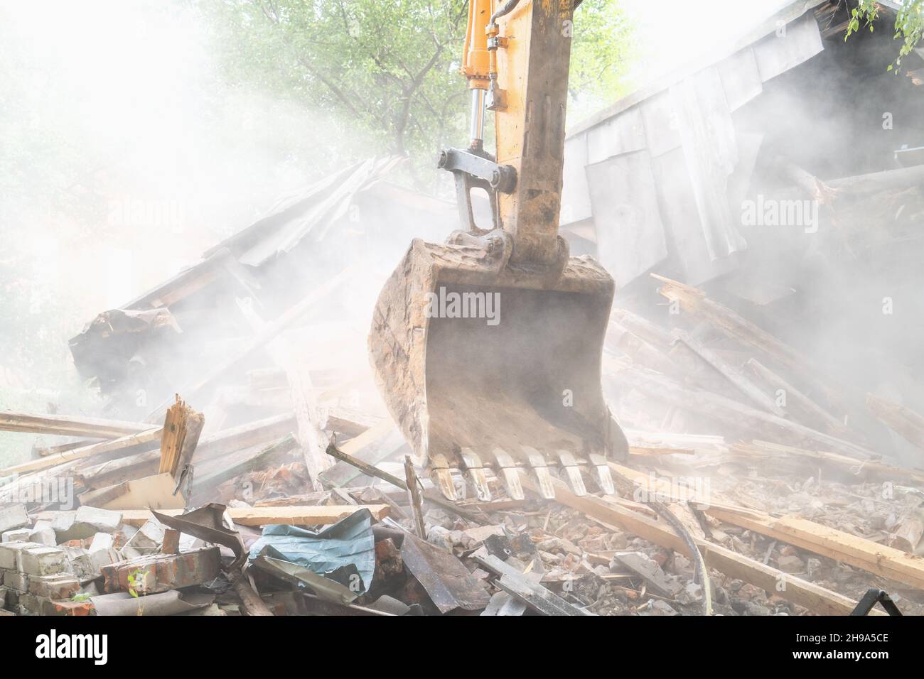 Excavator bucket in dust. Building demolition. Structure dismantling ...