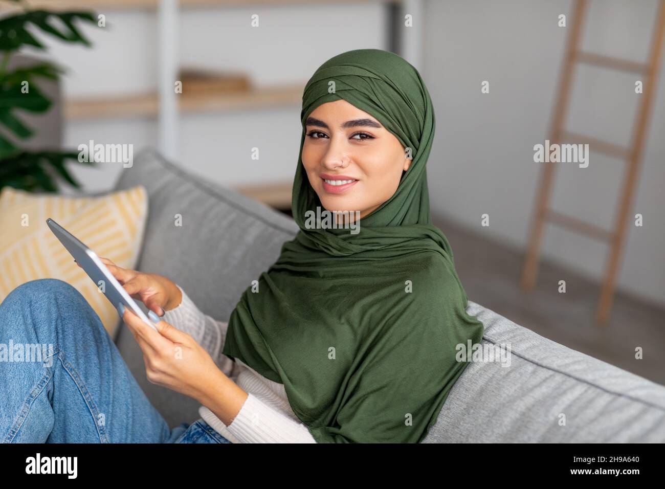 Millennial Arab woman in hijab using tablet pc for work, communication ...