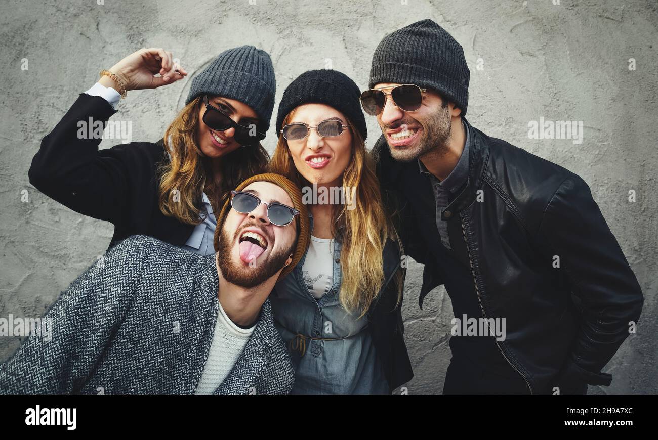Group of funky young people making crazy faces standing against a ...
