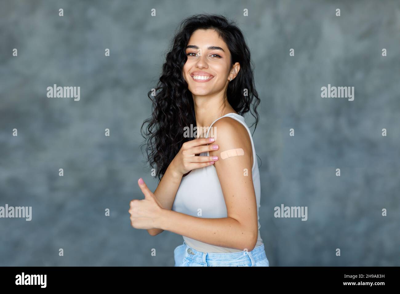 Young woman showing hand with band aid after injection, gesturing thumb ...