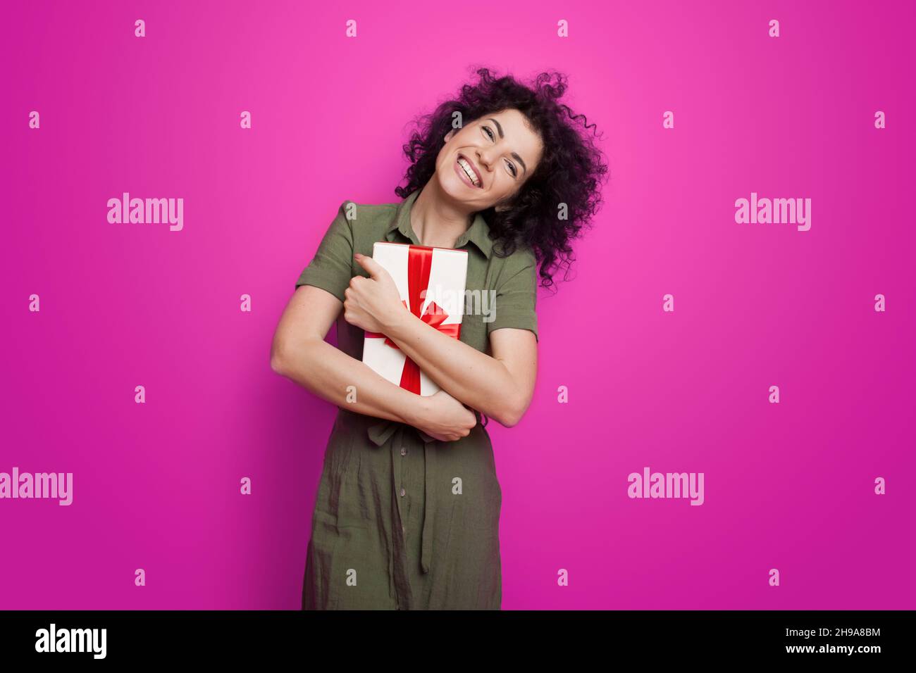 Happy caucasian woman hugging gift box isolated over pink background ...
