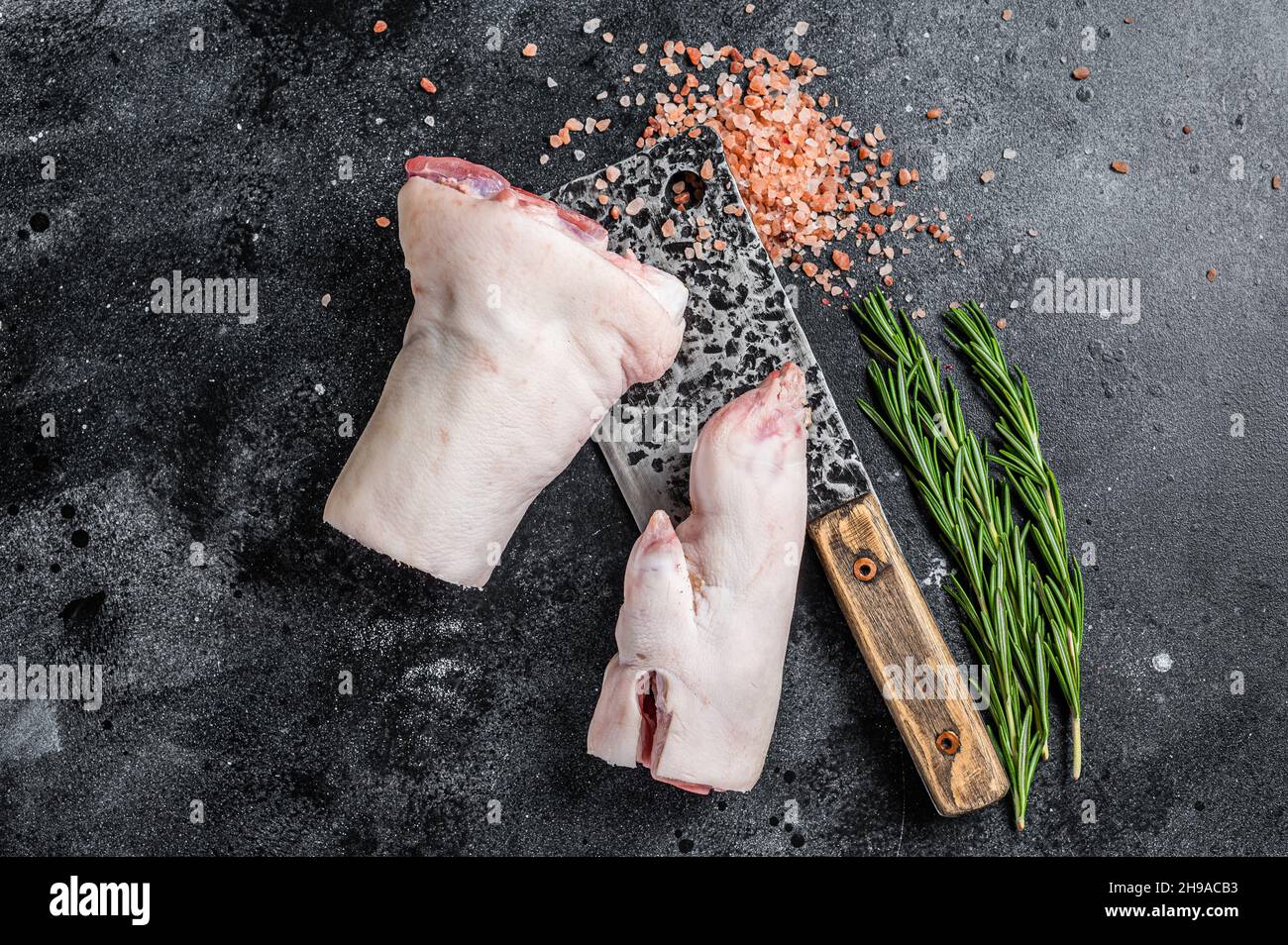 Butcher shop - Raw pork hoof, knuckle, feet on a cutting board. Black ...
