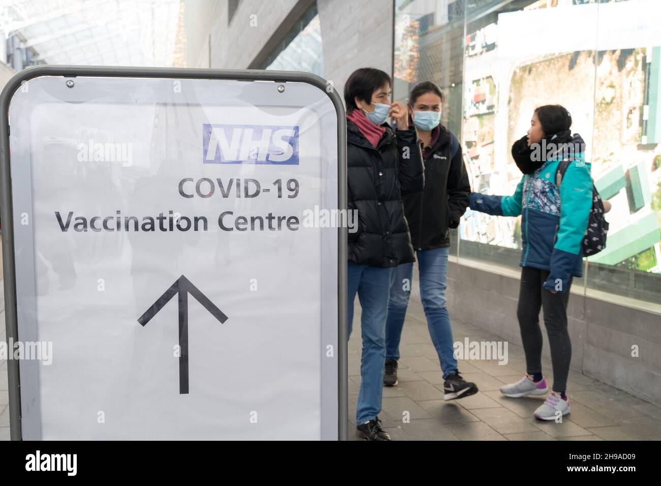 People stand beside the signage pointing to Covid-19 Vaccination Centre ...