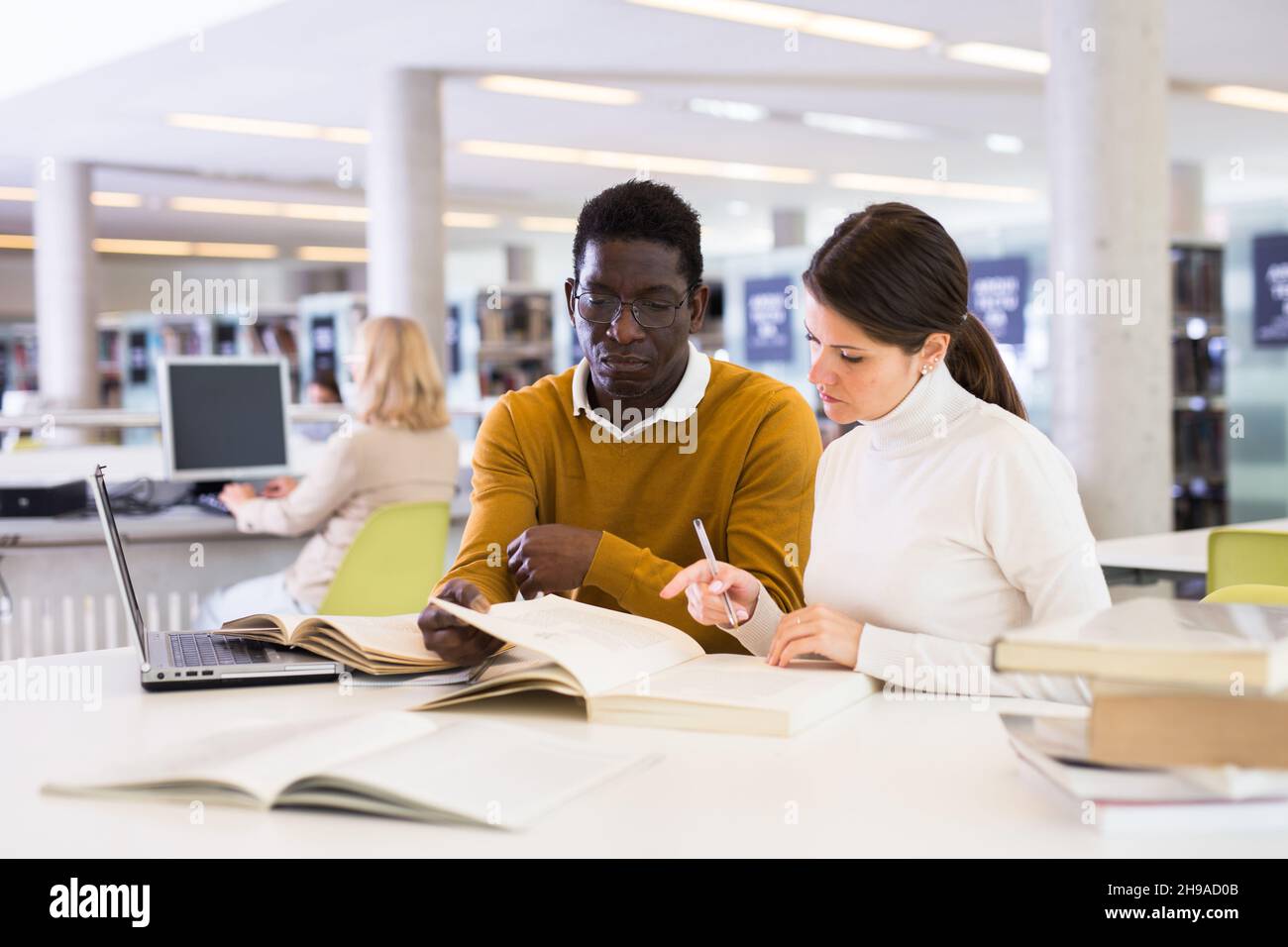 Couple of adult students studying together in public library Stock ...