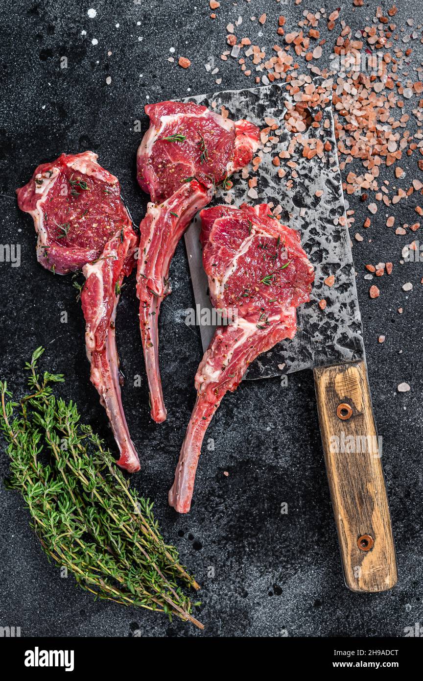 Raw uncooked lamb mutton meat chops steaks on a butcher cleaver. Black ...