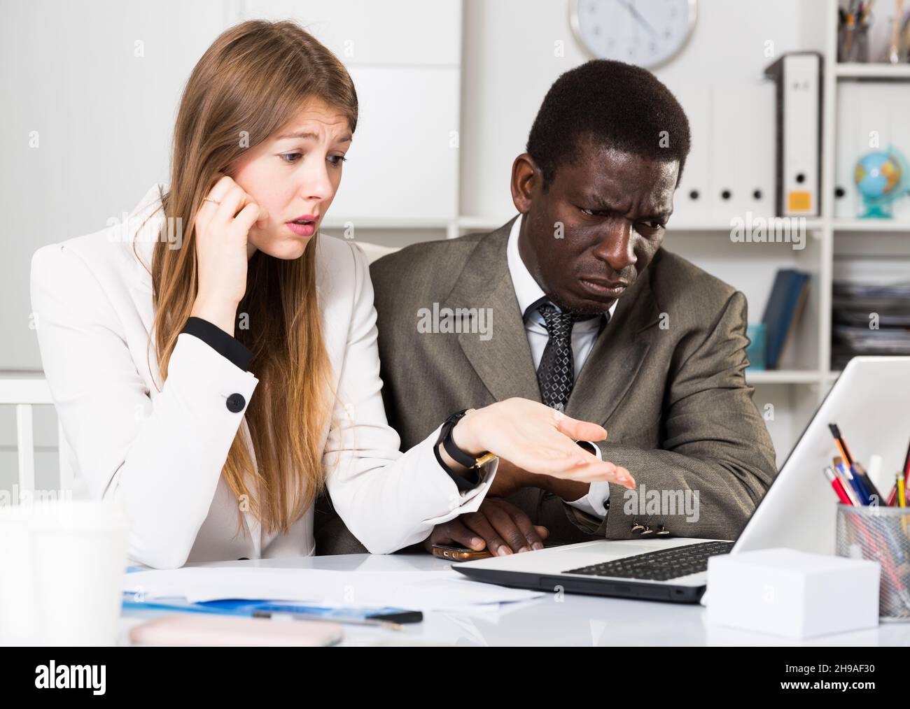 Upset woman and man colleagues working with laptop and papers Stock ...
