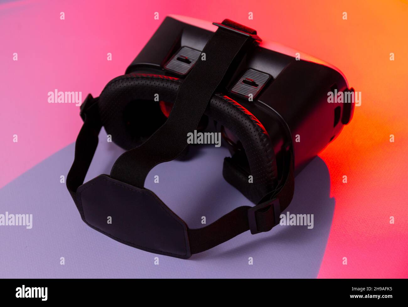Virtual reality glasses, headphones on a pink background with orange ...