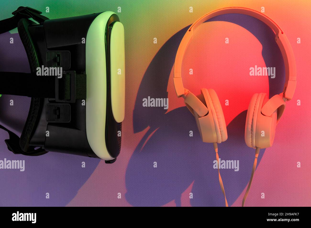 Virtual reality glasses, headphones on the orange background with pink ...