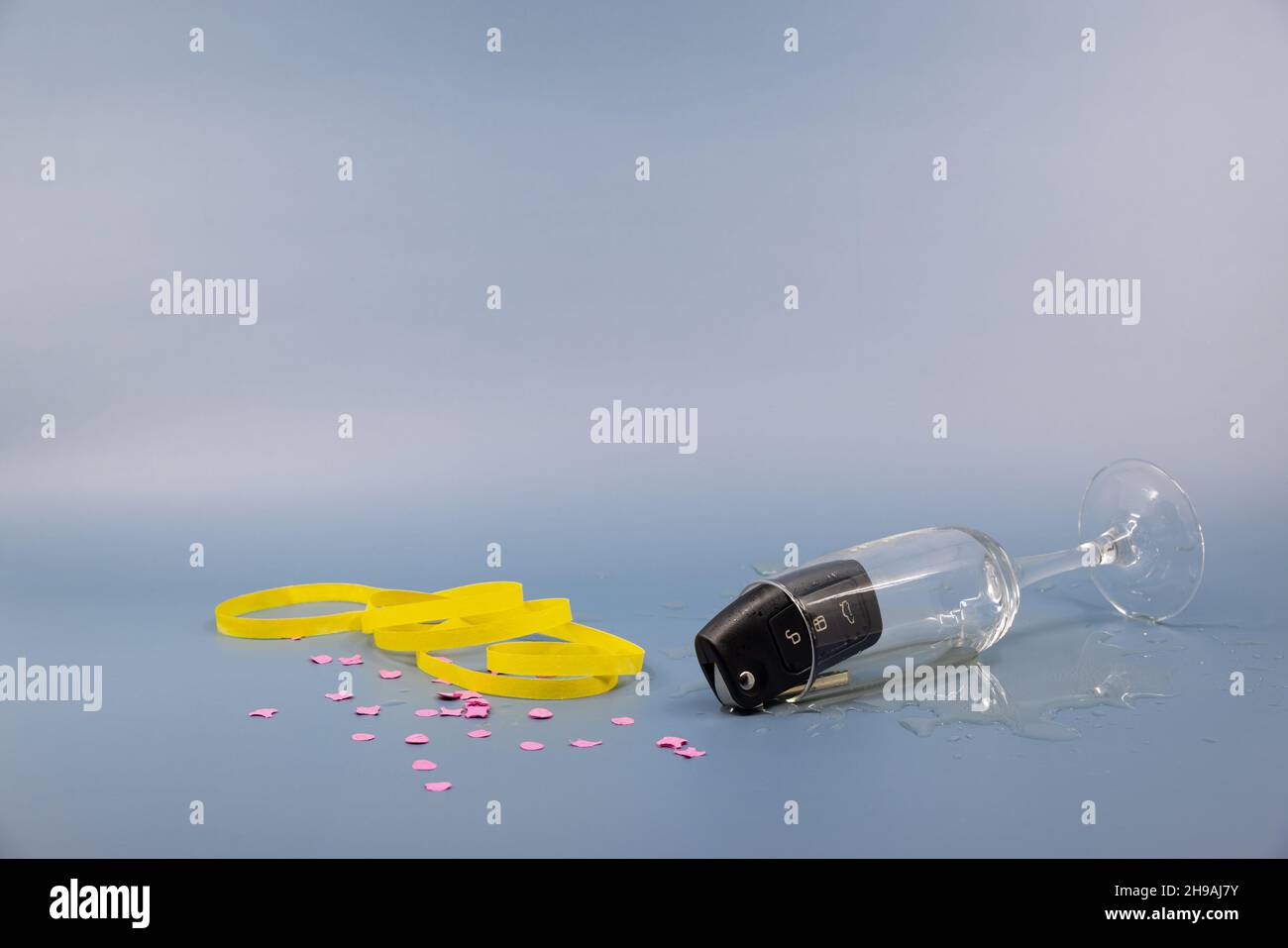 tipped over glass of sparkling wine with black car key in the glass ...