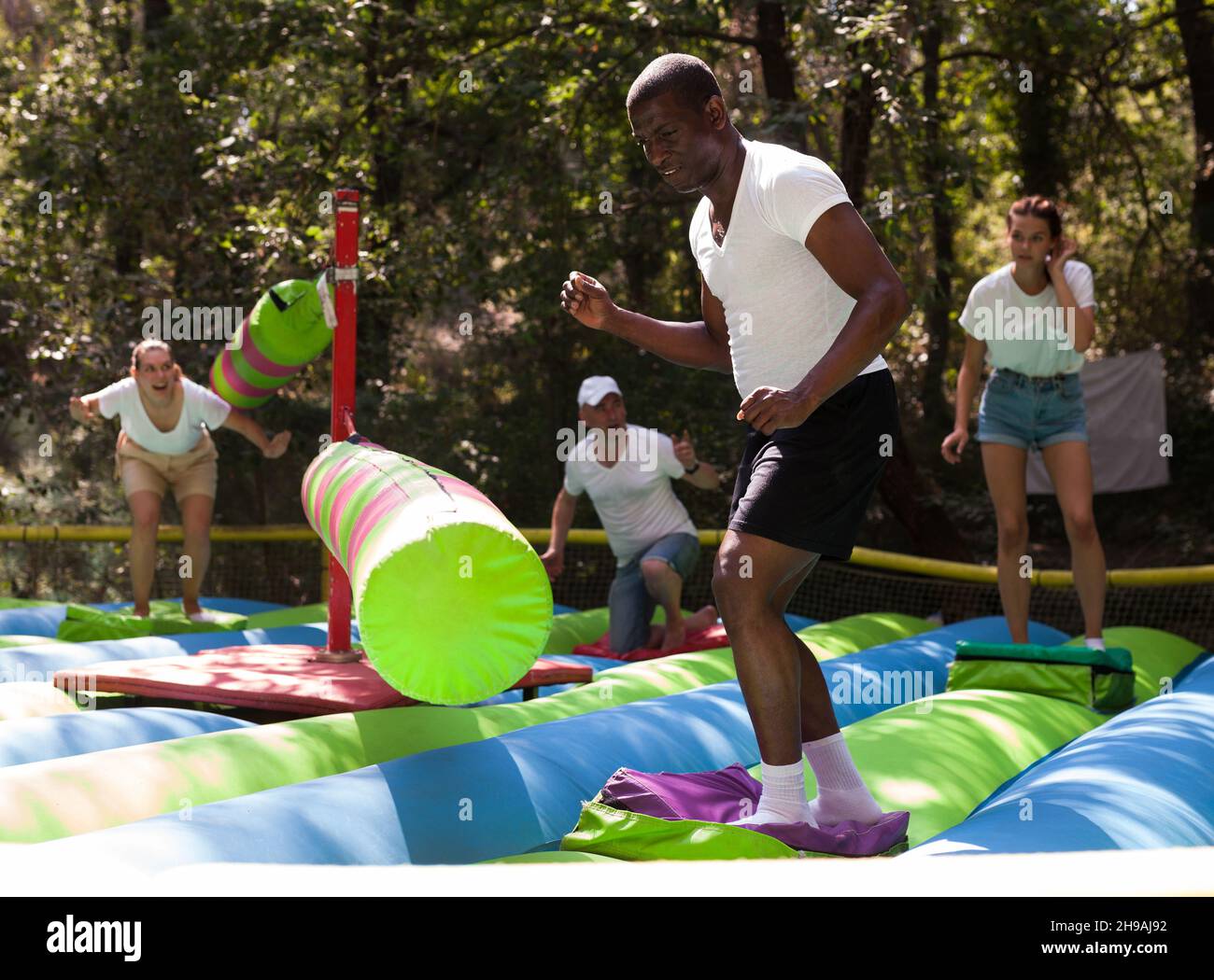 Team of friends having fun on an inflatable trampoline in an attraction ...